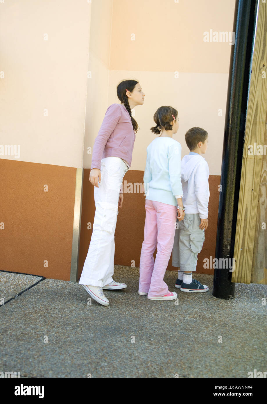 Line of children peeking around wall Stock Photo - Alamy