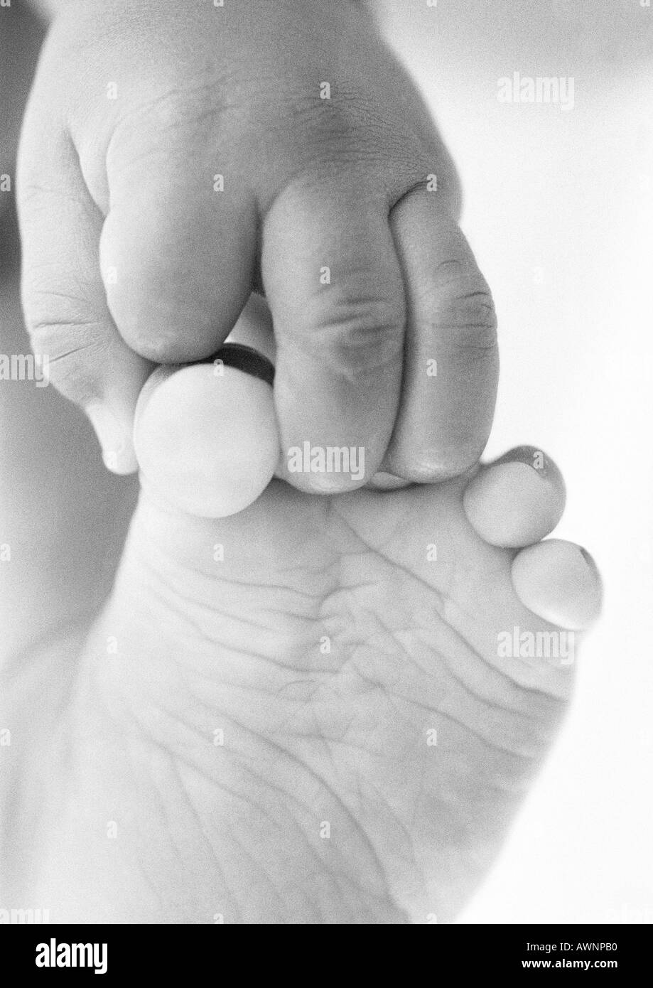 Baby's hand on foot, close-up, b&w Stock Photo - Alamy