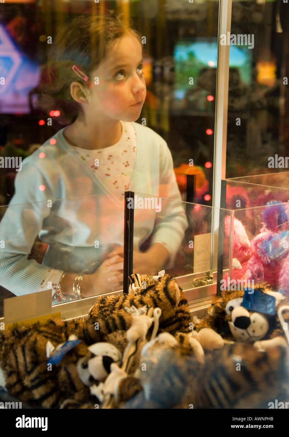 Girl looking through glass of toy grabbing game Stock Photo - Alamy