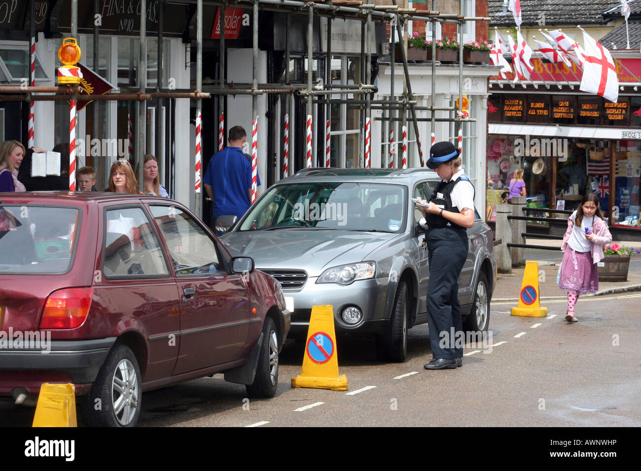 A female police community support officer takes notes about cars parked ...