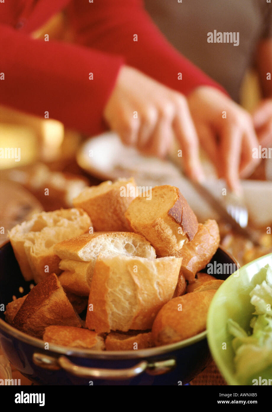 Breadbasket, hands holding fork and knife in background, close-up Stock ...