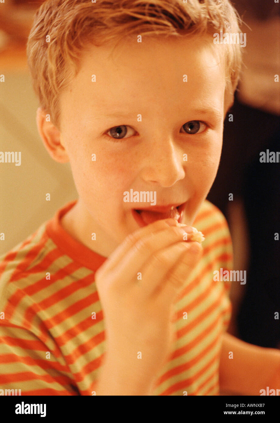 Child putting food in mouth, looking at camera, portrait Stock Photo ...