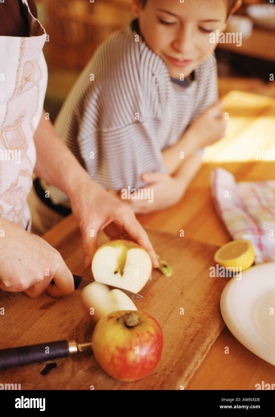 Hands cutting apples, child leaning on counter watching Stock Photo - Alamy