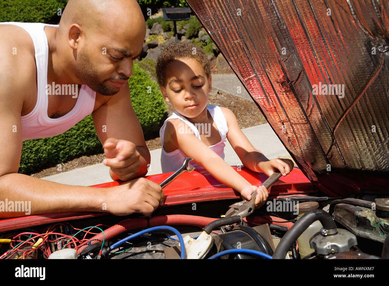 Young boy helping his father work on car Stock Photo - Alamy