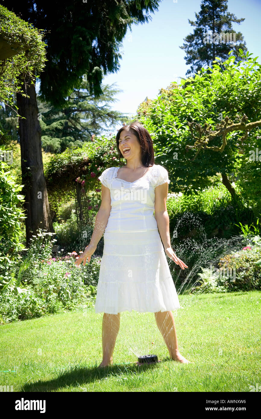 Woman standing in sprinkler in her backyard Stock Photo - Alamy