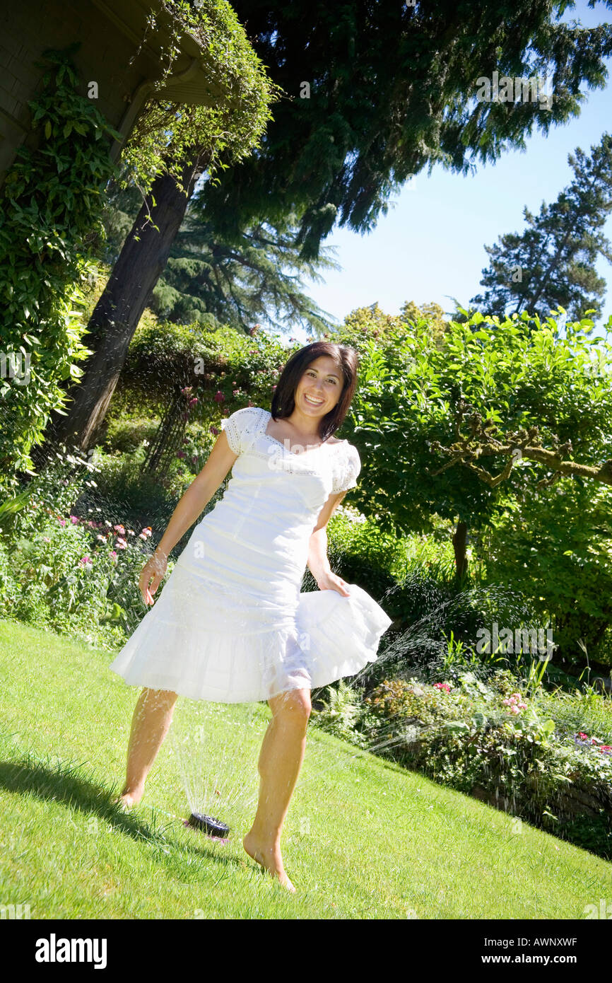 Woman standing in sprinkler in her backyard Stock Photo - Alamy