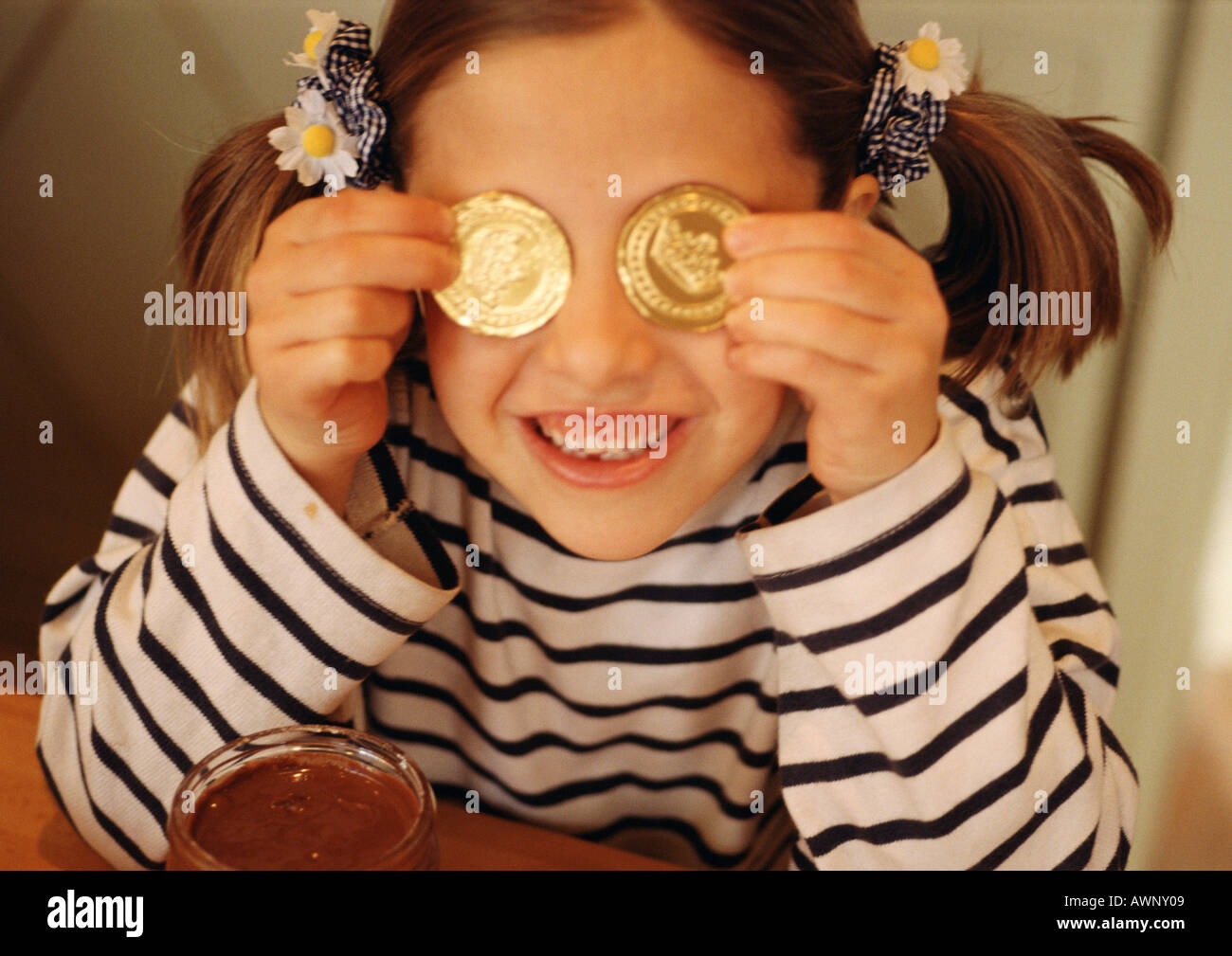 Child holding gold coins in front of eyes, smiling Stock Photo - Alamy