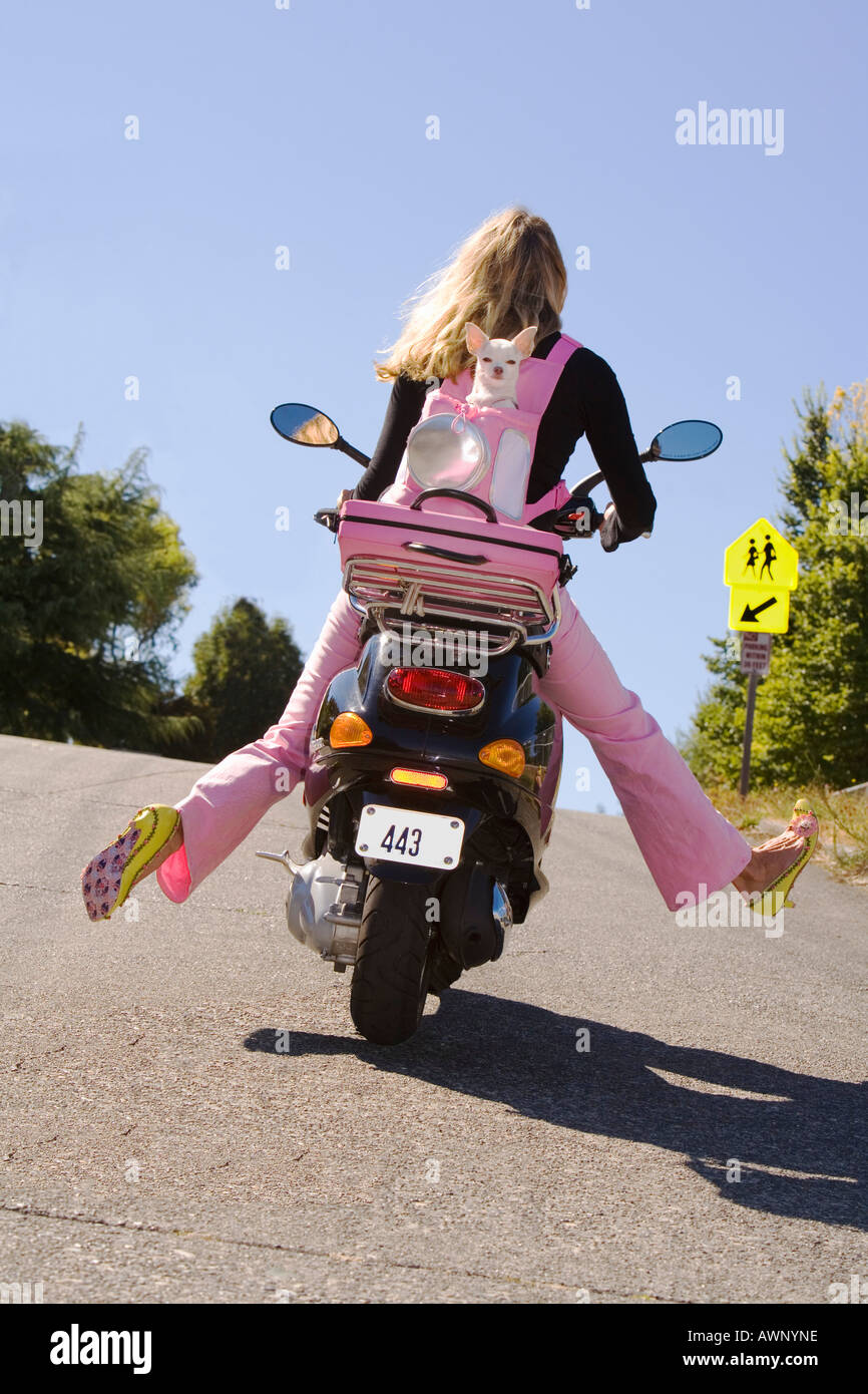 Woman riding a scooter with extended legs Stock Photo - Alamy