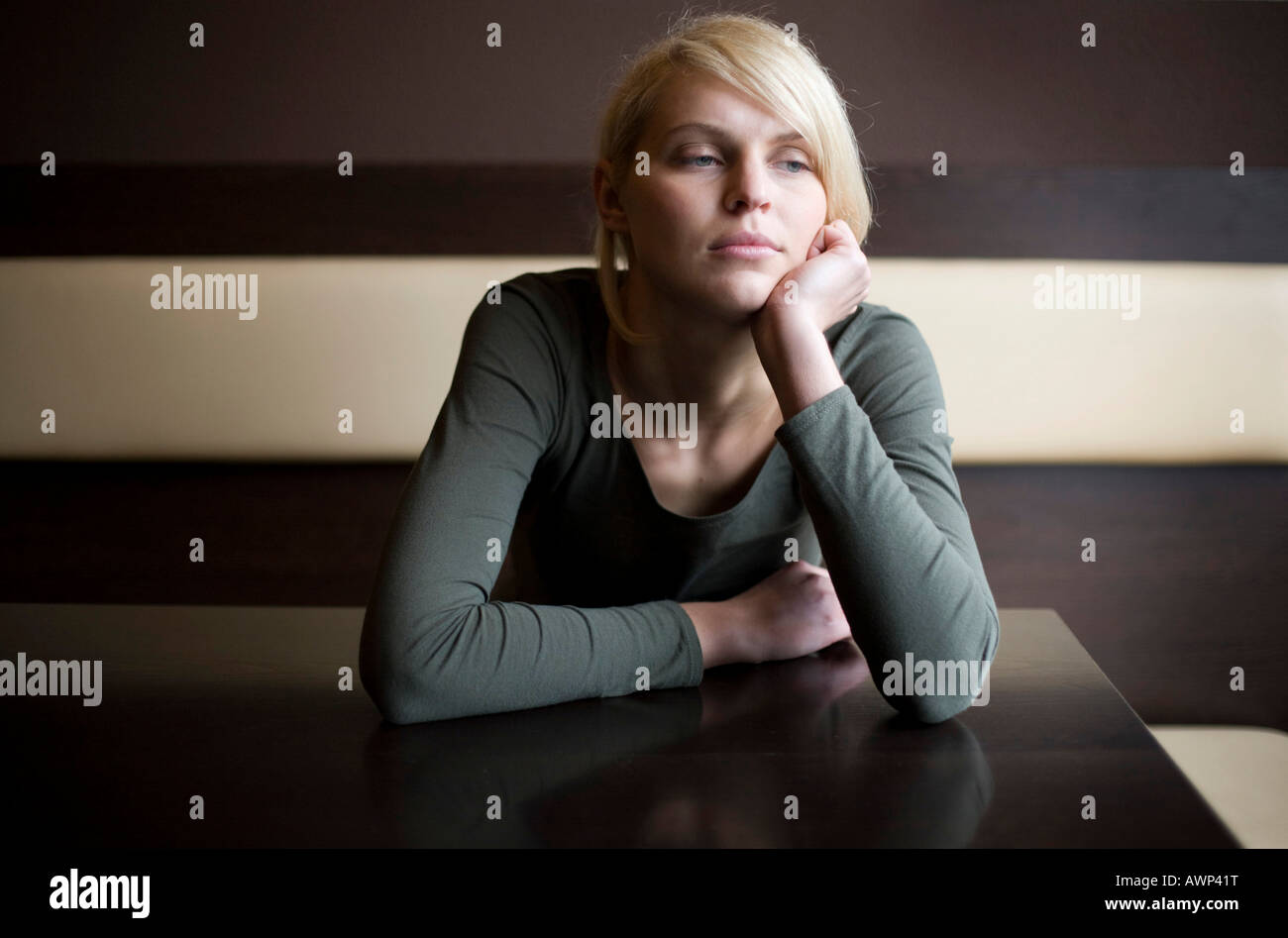 Young woman looking sad sitting at a table in a bar Stock Photo - Alamy