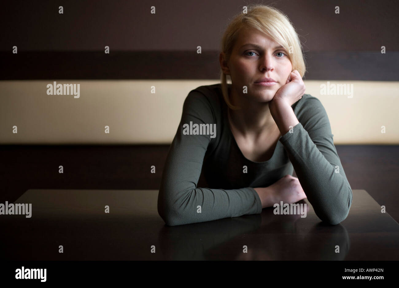 Blonde woman looking sad sitting at a table in a bar Stock Photo - Alamy