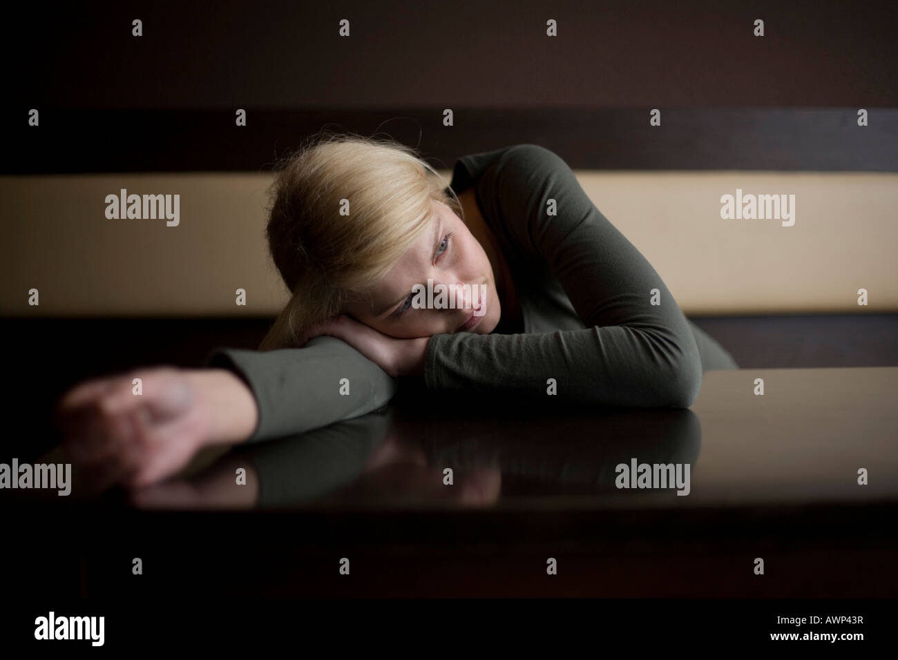 Blonde woman looking sad leaning her body over a table in a bar Stock ...