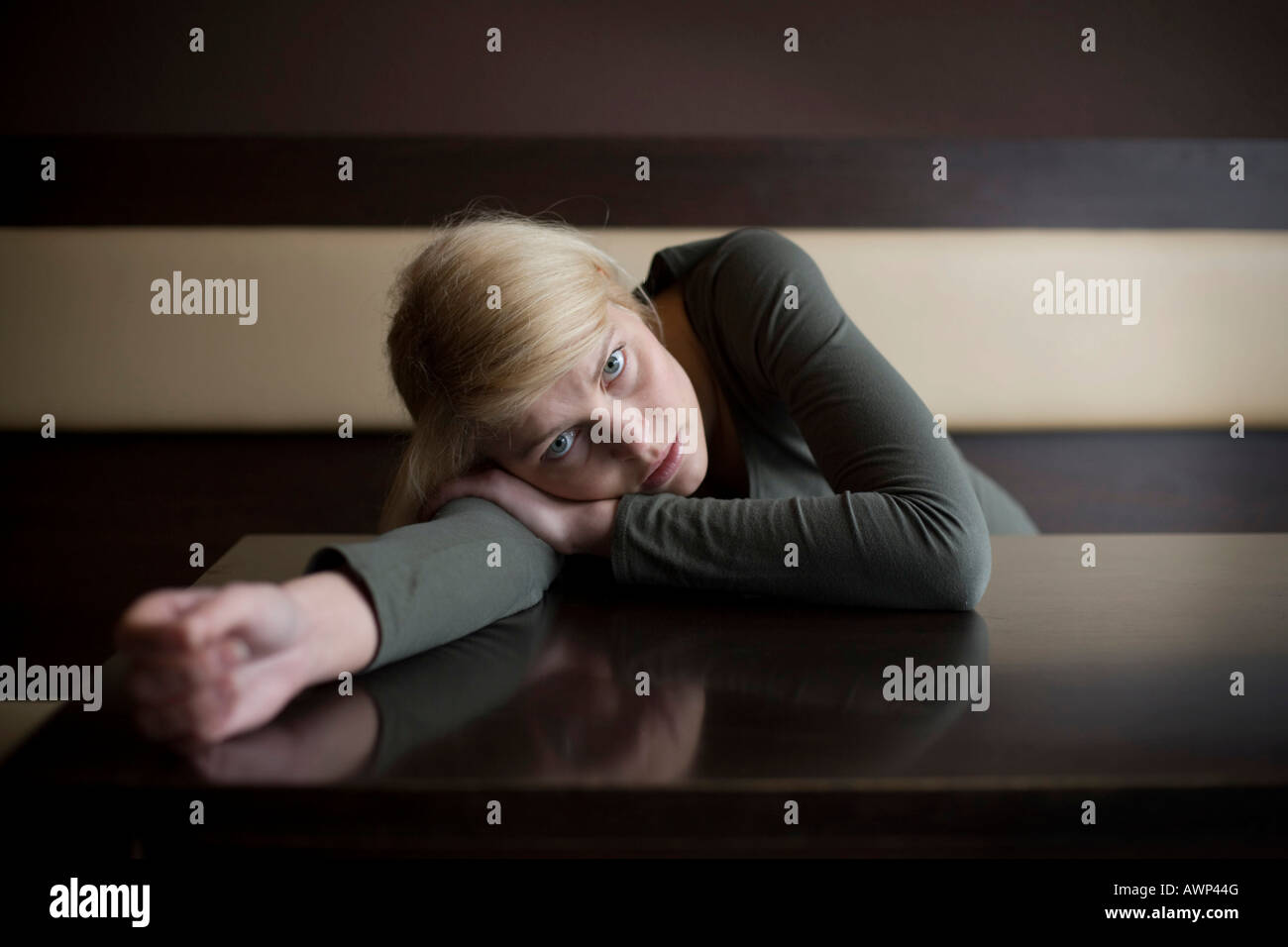 Blonde woman looking sad leaning her body over a table in a bar Stock ...