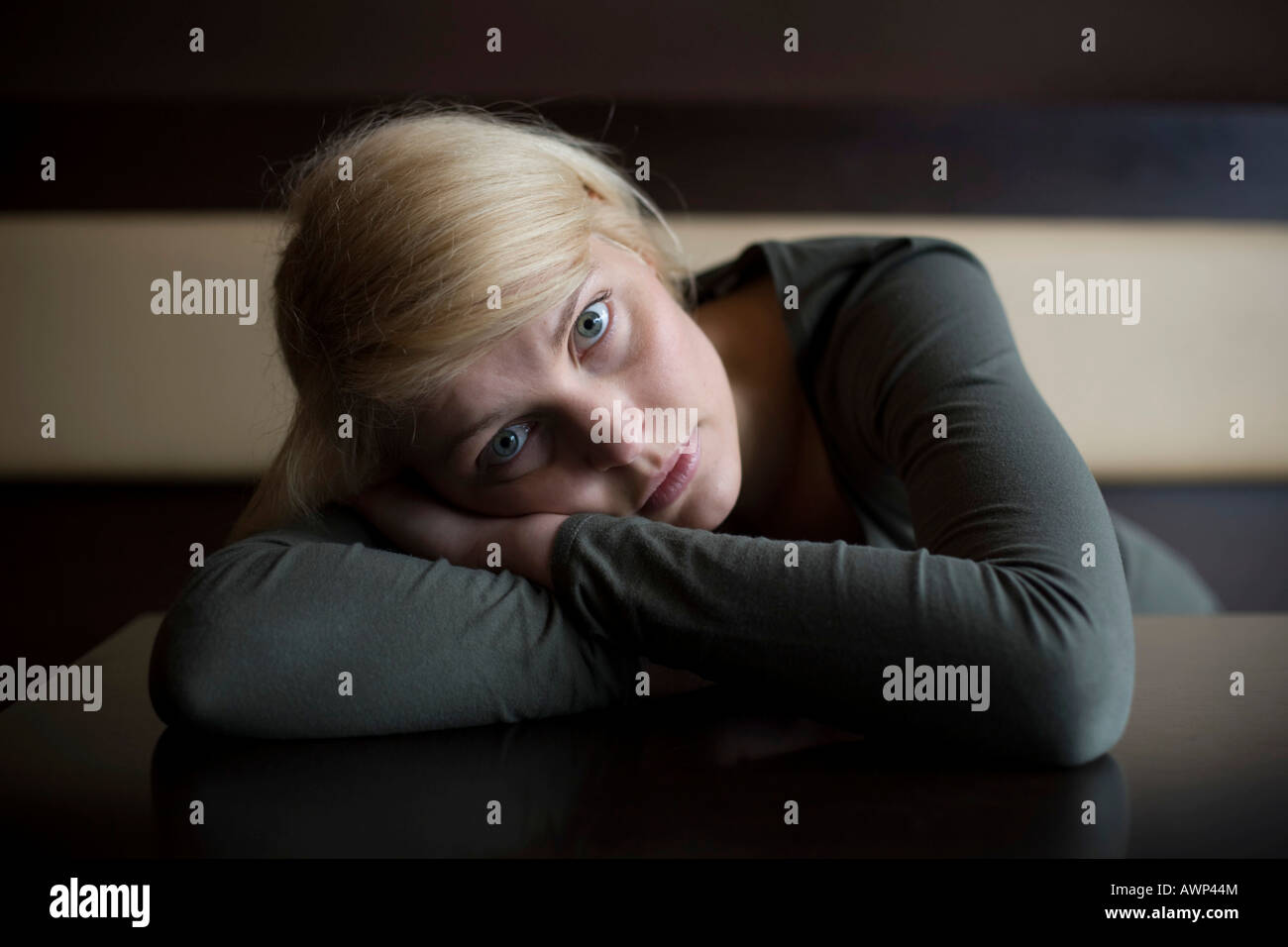 Blonde woman looking sad leaning her body over a table in a bar Stock ...