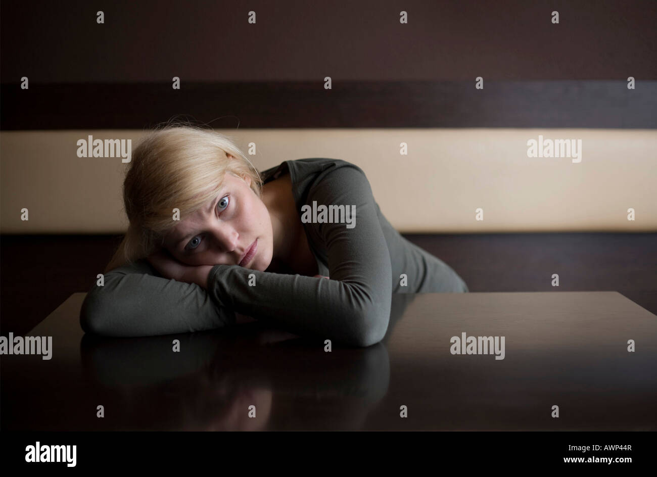 Blonde woman looking sad leaning her body over a table in a bar Stock ...