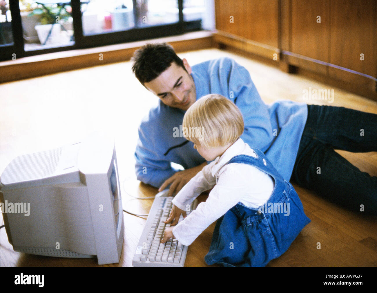 Man lying on floor, child in front of computer Stock Photo - Alamy