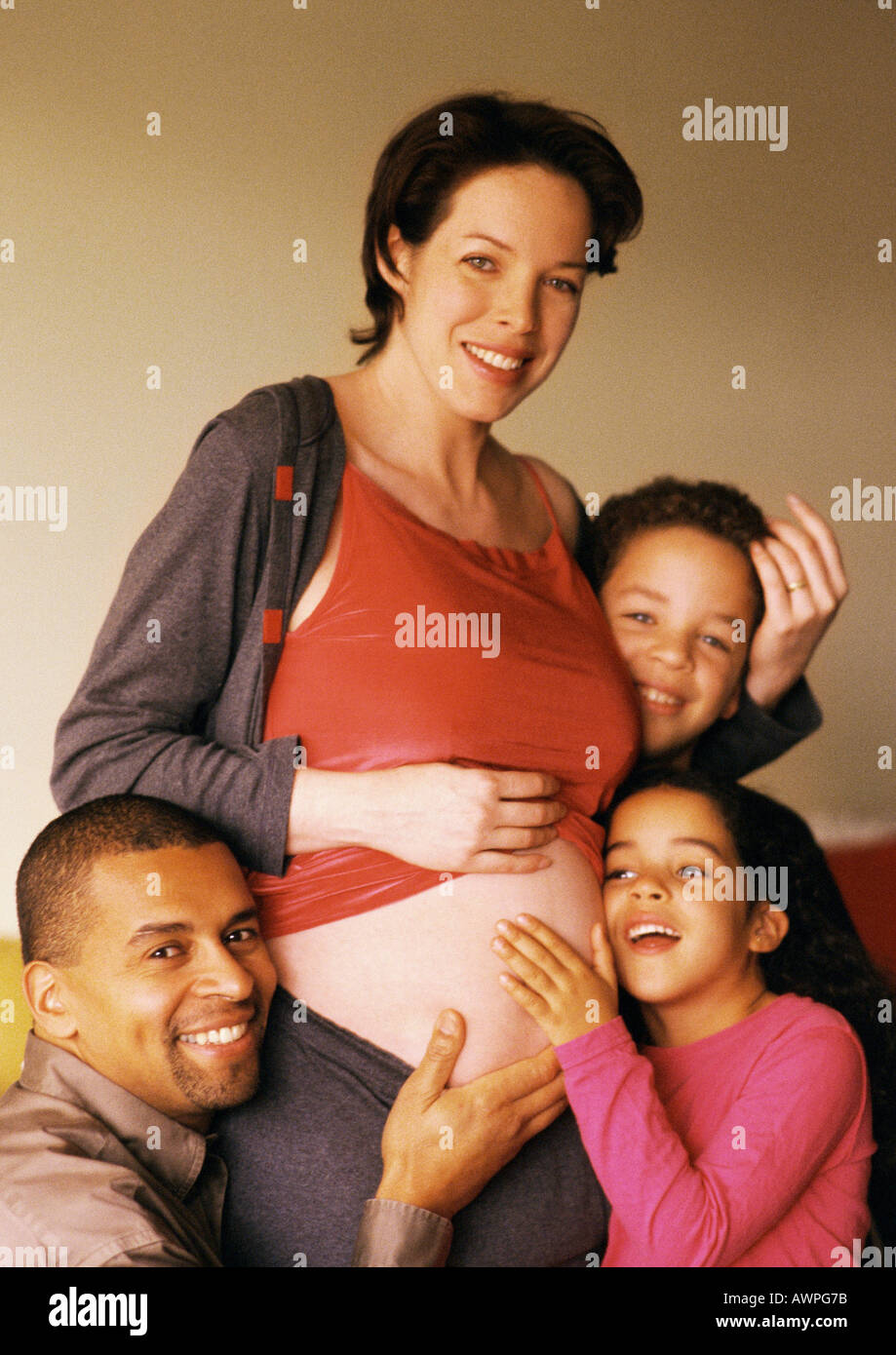 Man and children around pregnant woman's exposed stomach Stock Photo ...