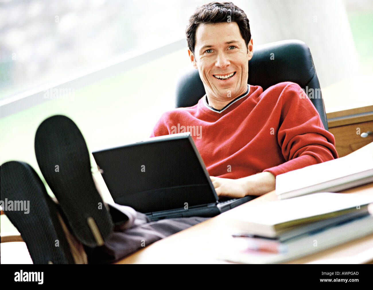 Man sitting with feet up and laptop on lap Stock Photo - Alamy