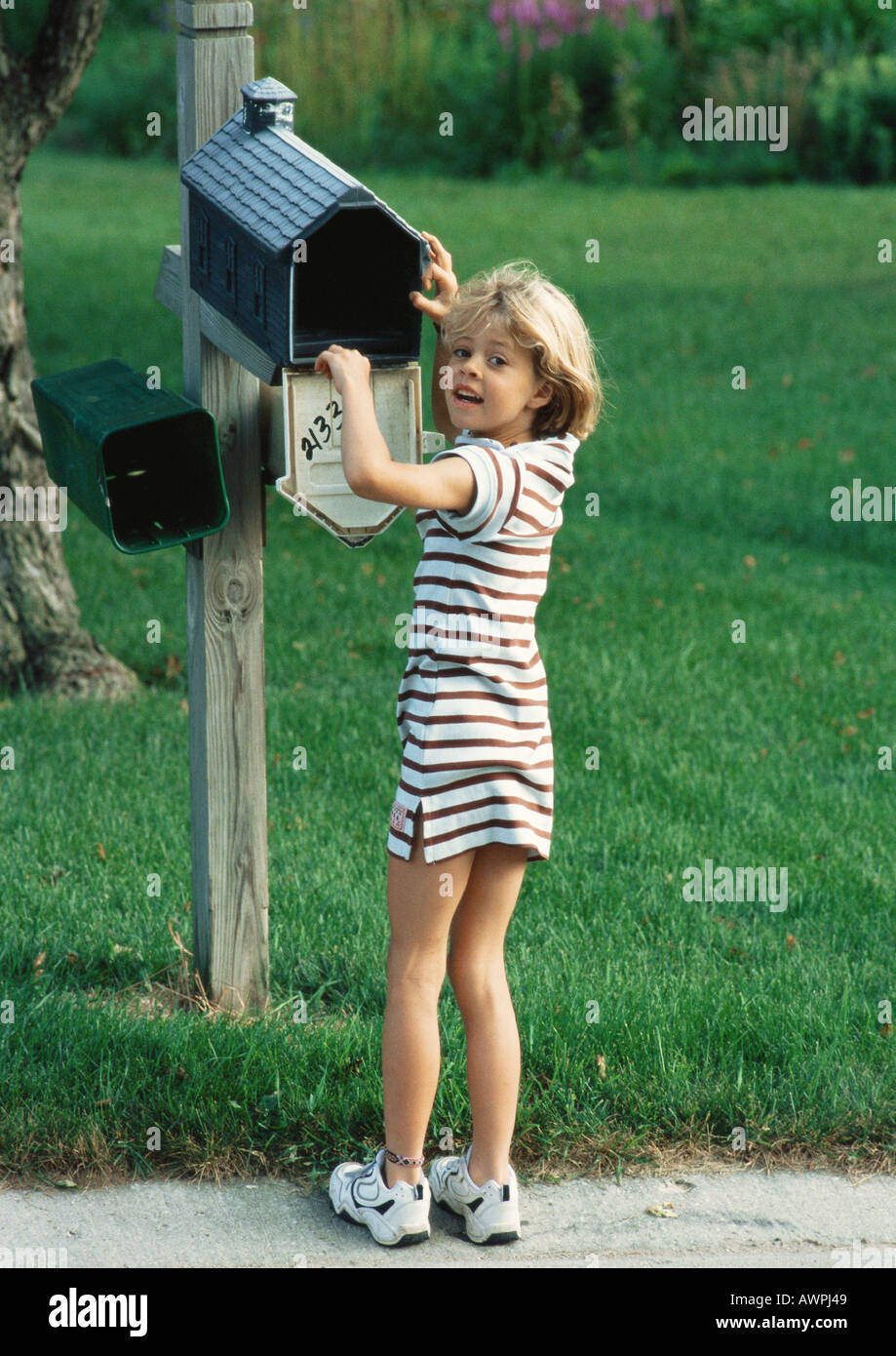 Girl with hand in mailbox, looking into camera Stock Photo - Alamy