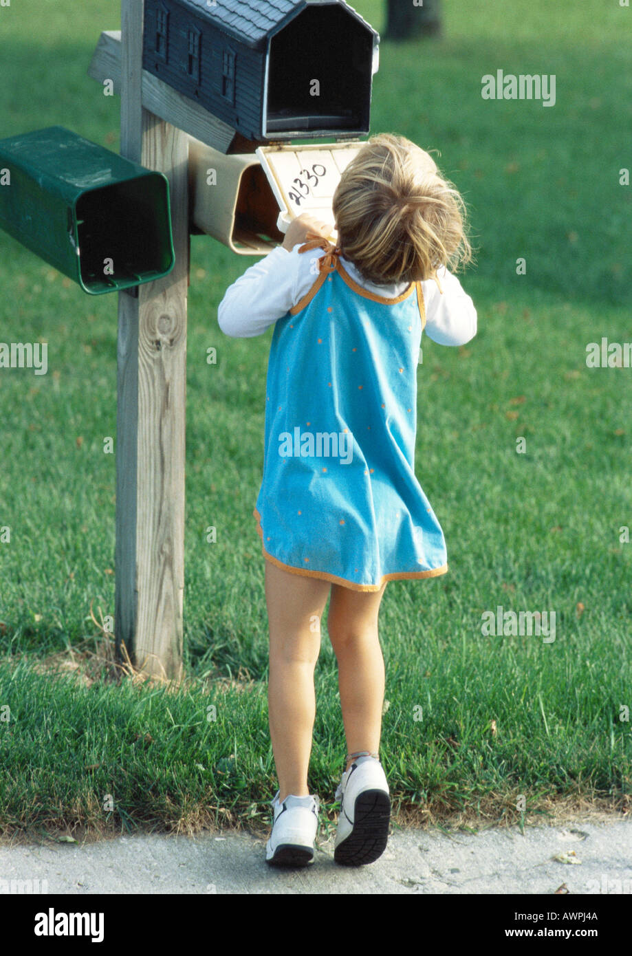 Girl looking into mailbox, rear view Stock Photo - Alamy