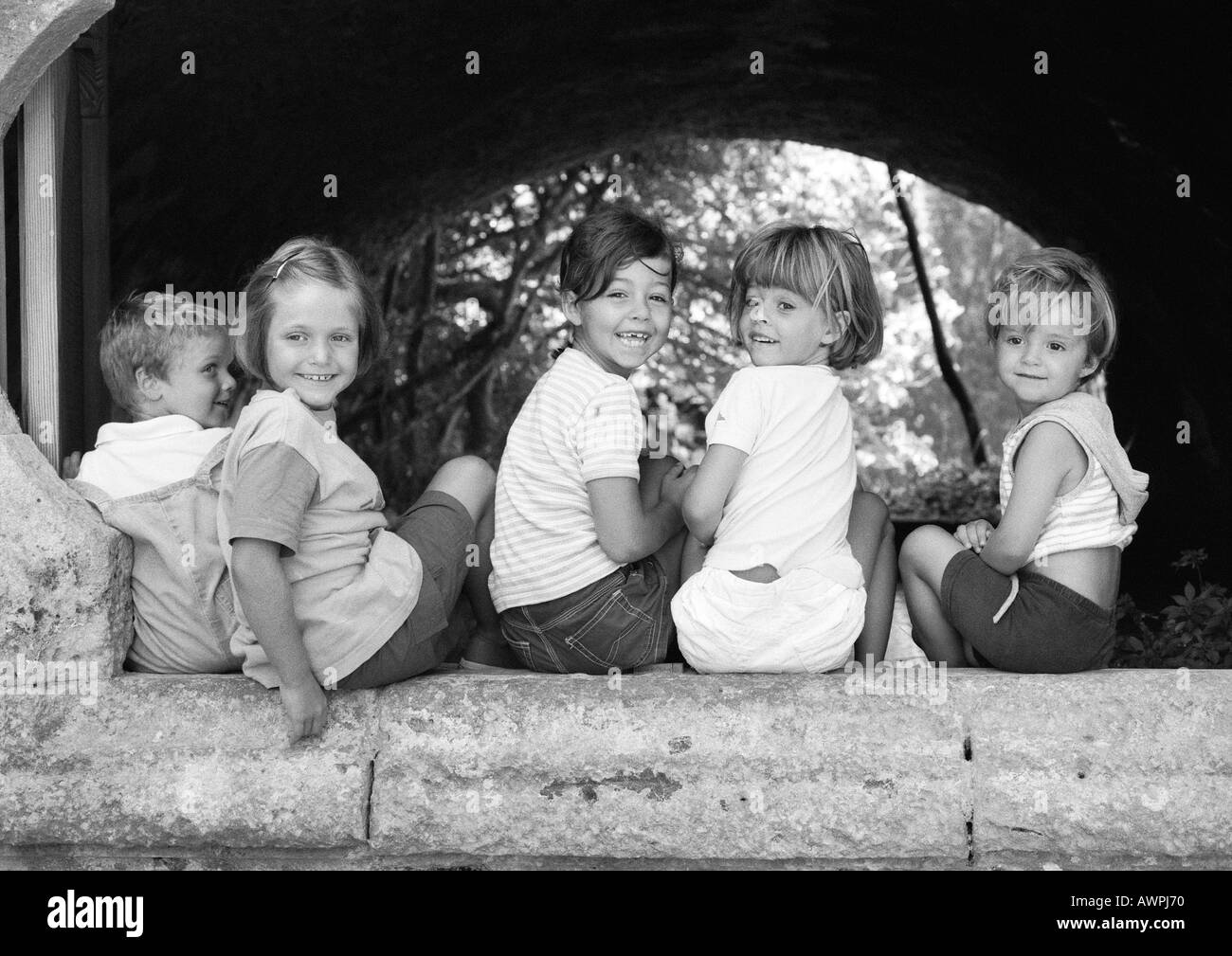 Five children sitting under an arch, b&w Stock Photo - Alamy