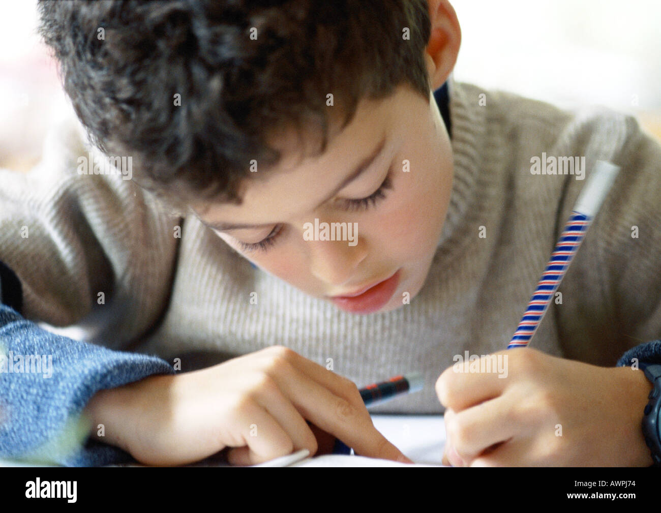 Boy bending head over notebook, writing, close-up Stock Photo - Alamy
