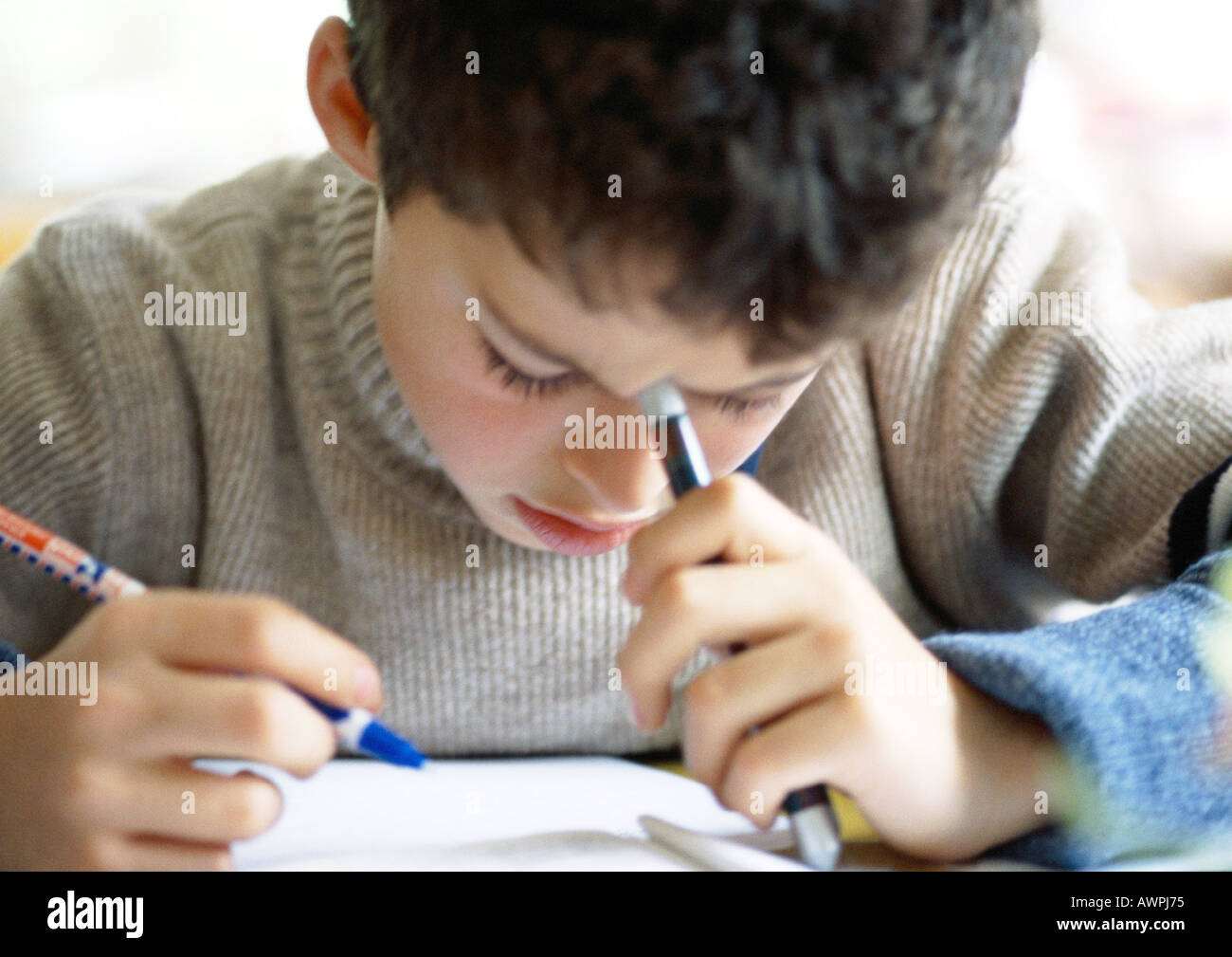 Boy bending head over notebook, writing, close-up Stock Photo - Alamy