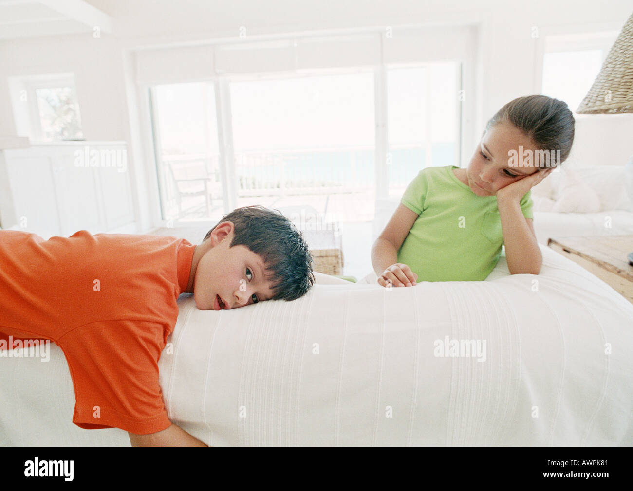 Two children resting on bed, one looking at camera Stock Photo - Alamy