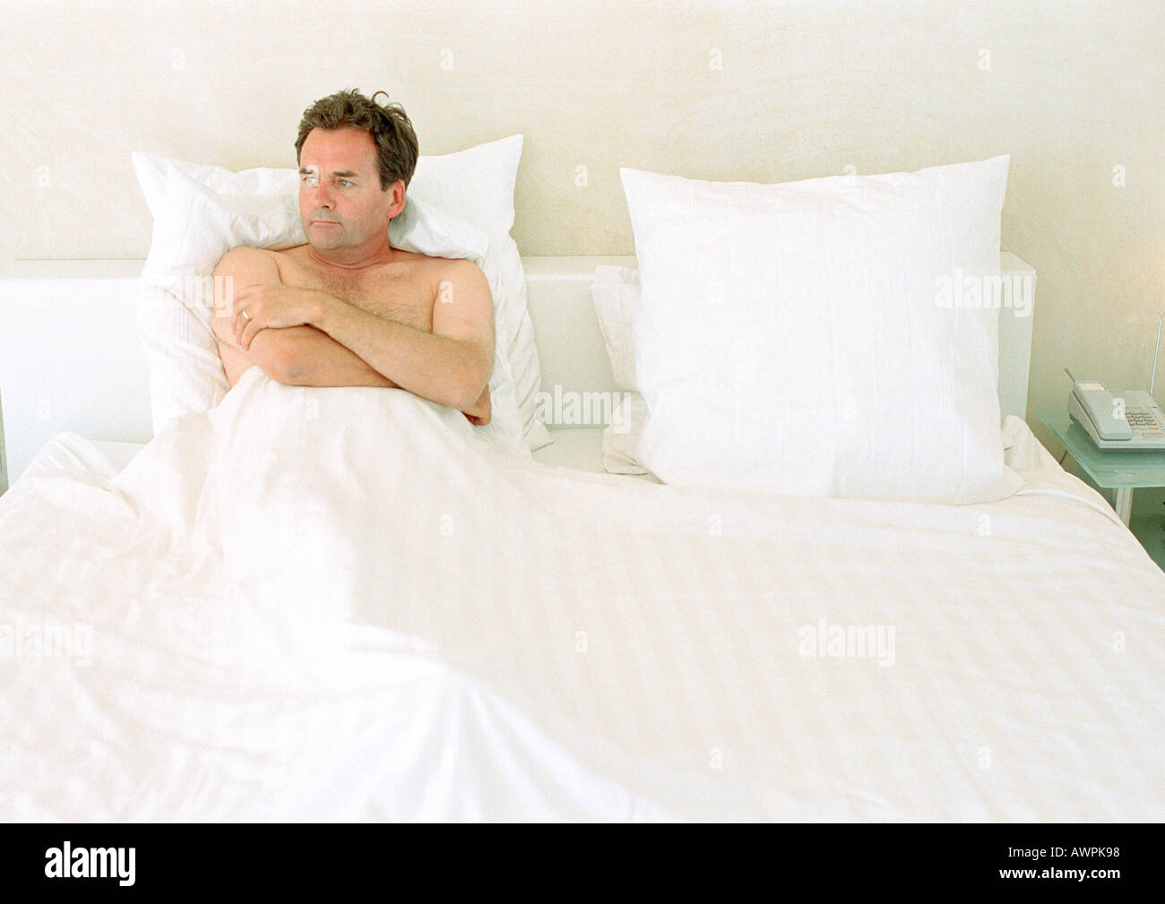 Man lying in bed, arms folded over chest Stock Photo - Alamy