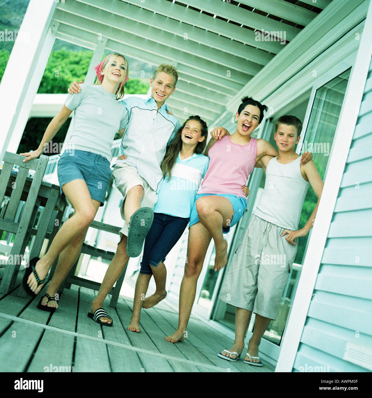 Young people standing with arms around each other's shoulders on porch ...
