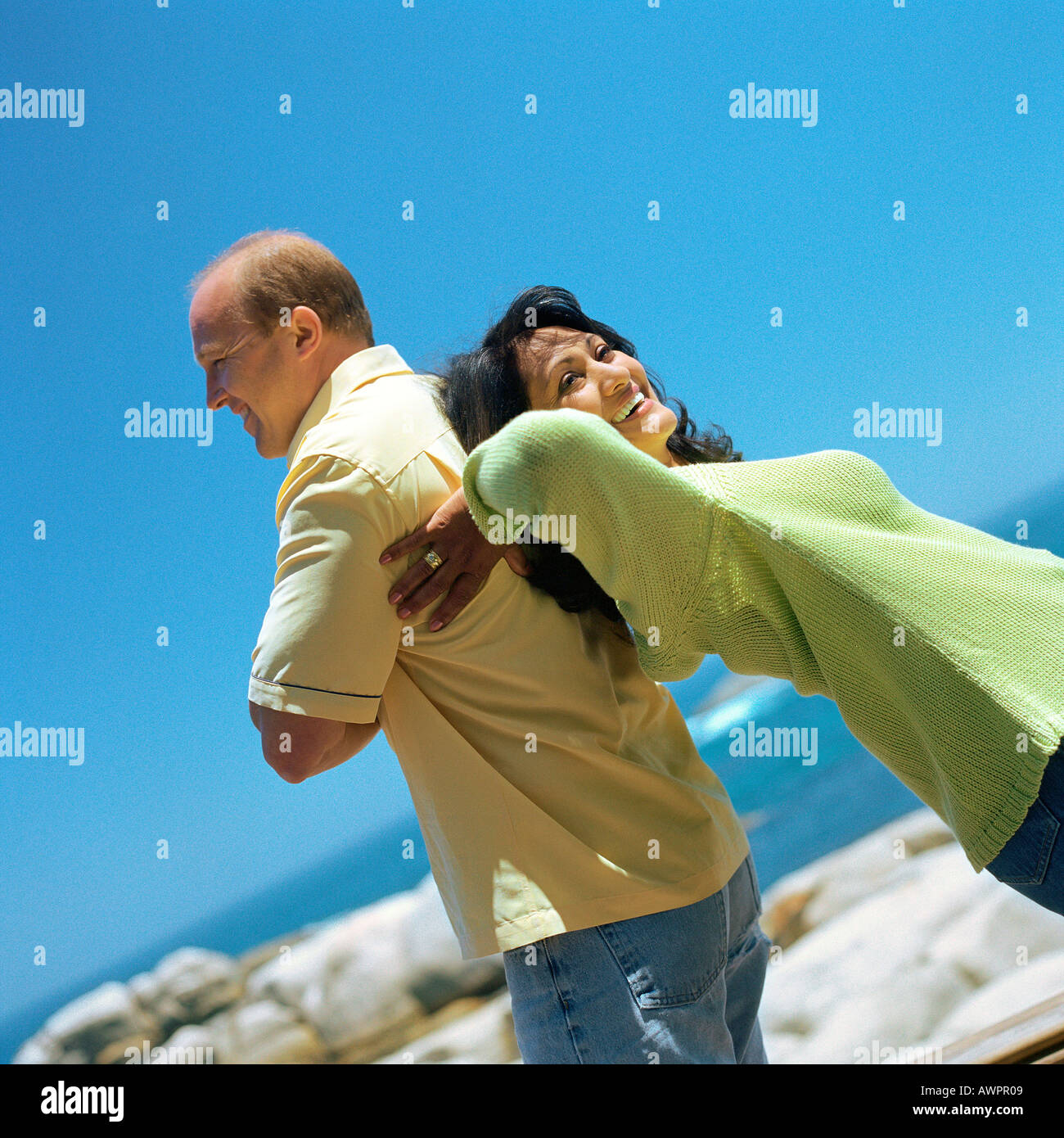 Couple standing back to back outside, smiling Stock Photo - Alamy