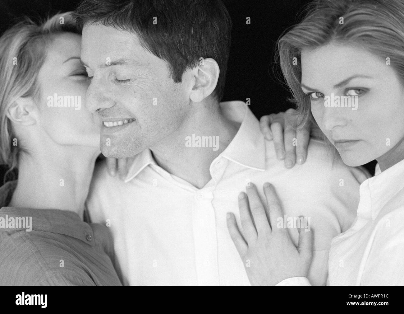 Man standing between two women, being kissed by one, b&w Stock Photo ...