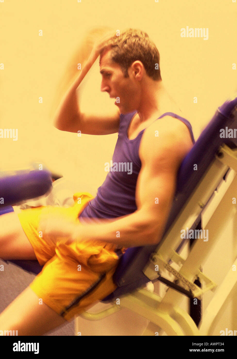 Man sitting on weight machine, side view Stock Photo - Alamy