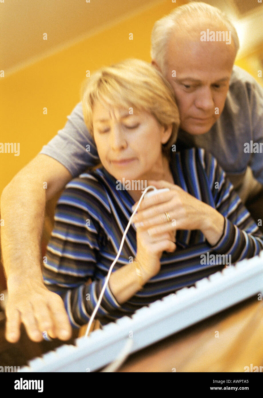 Mature couple, man pressing key on keyboard, woman holding computer ...
