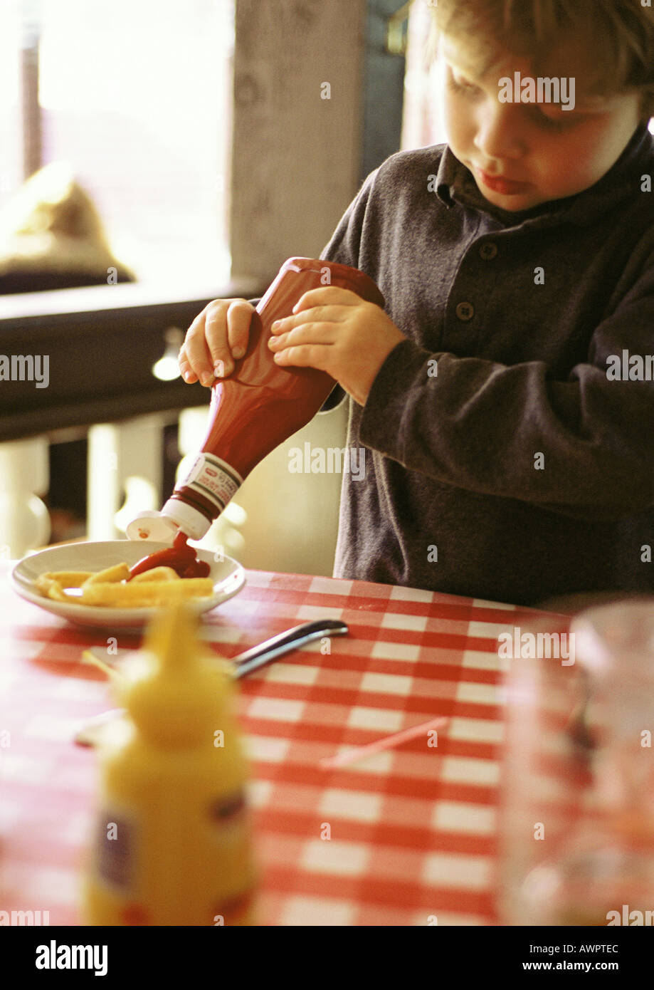 Little boy behind table with red and white checked tablecloth ...
