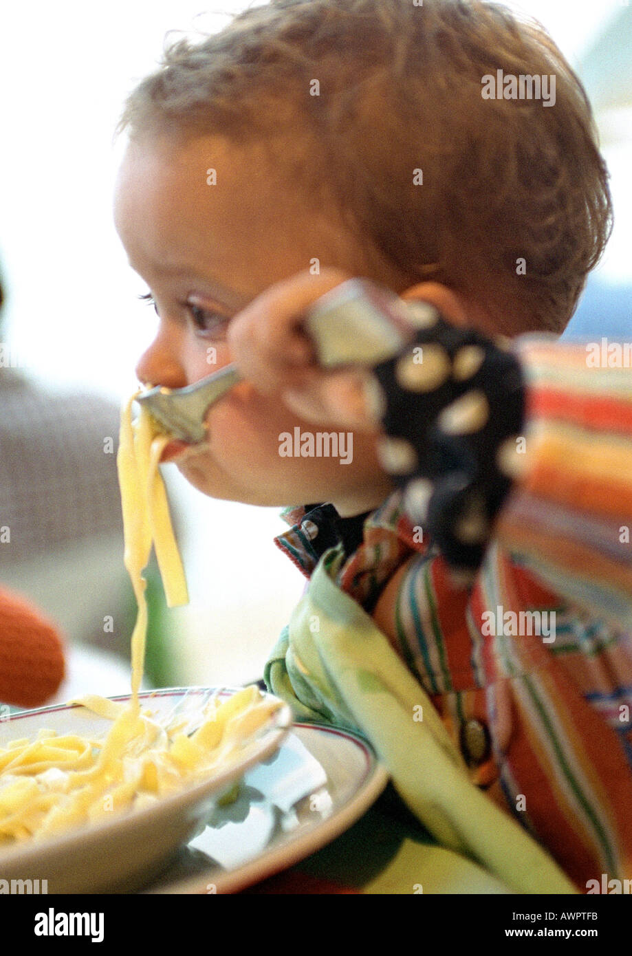 Baby eating pasta, side view Stock Photo - Alamy