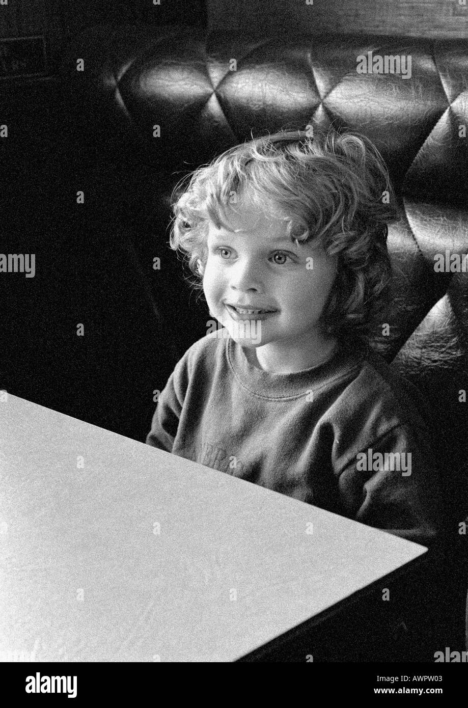 Child sitting at table smiling, portrait, b&w Stock Photo - Alamy