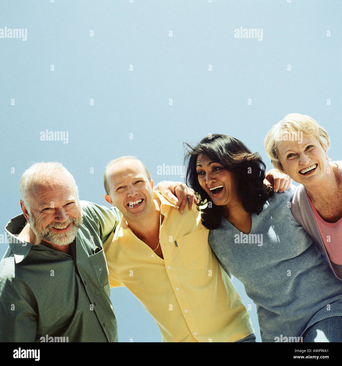 Two men and two women arms around each others' shoulder laughing and ...
