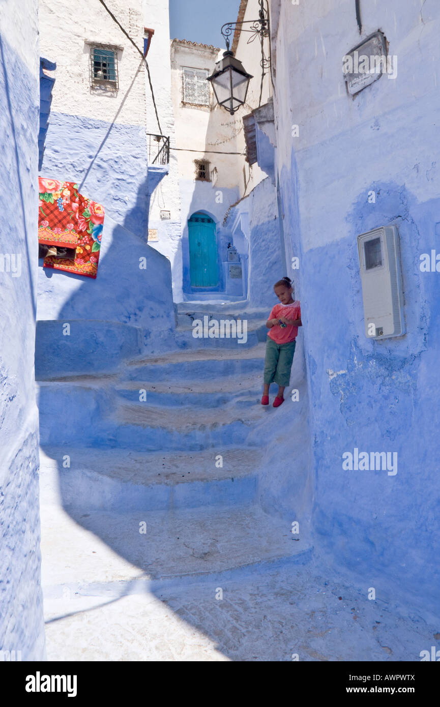 Young girl with colourful rug in blue alleyway, Chefchaouen Medina ...