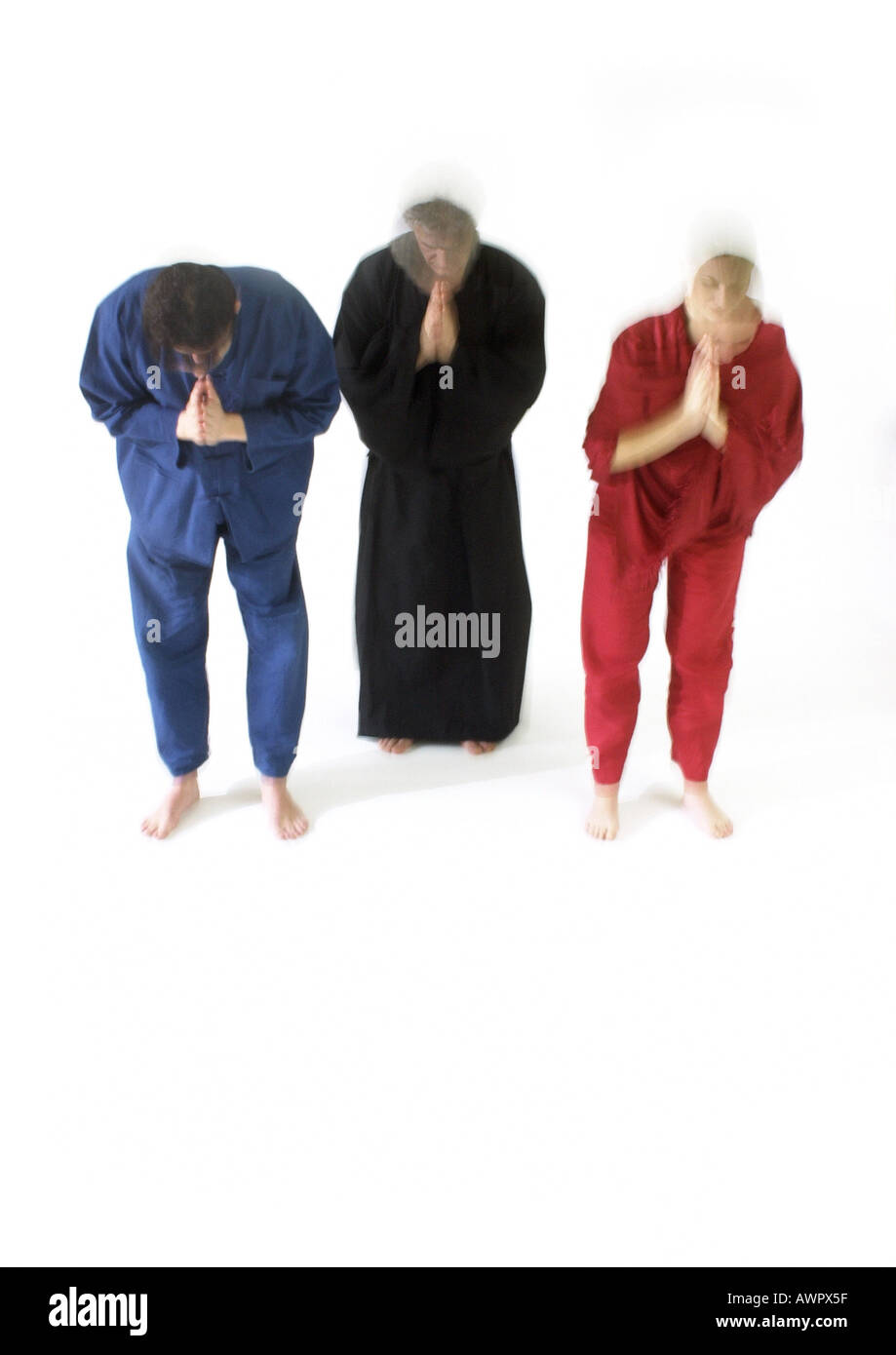 Three people standing, bending forward with hands together and eyes ...