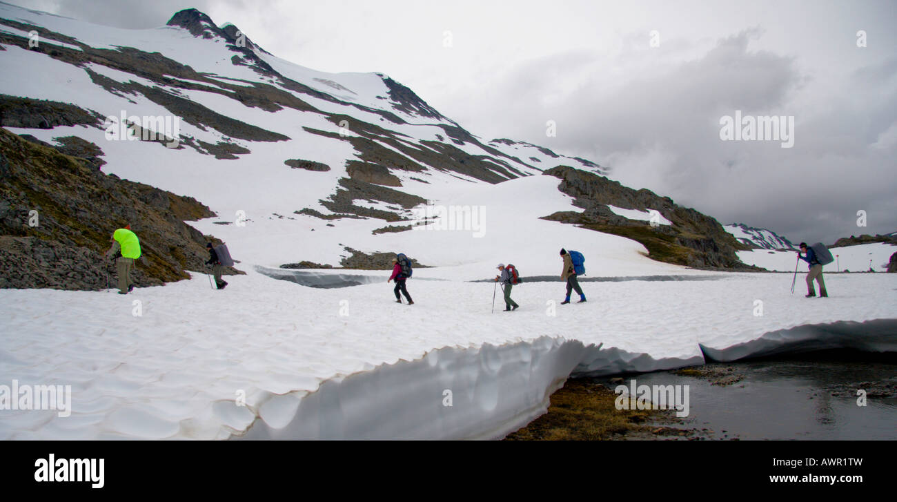 Hikers carrying backpacks crossing a snowy valley along the Chilkoot ...