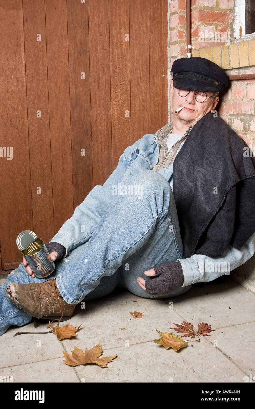 Smoking beggar with worn shoes asleep in the streets Stock Photo - Alamy