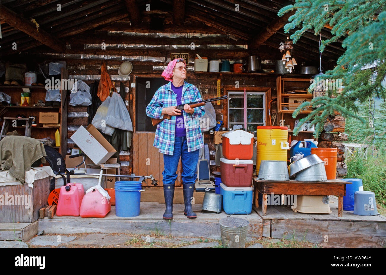 Armed woman standing in front of her log home, Brooks Range, Alaska ...