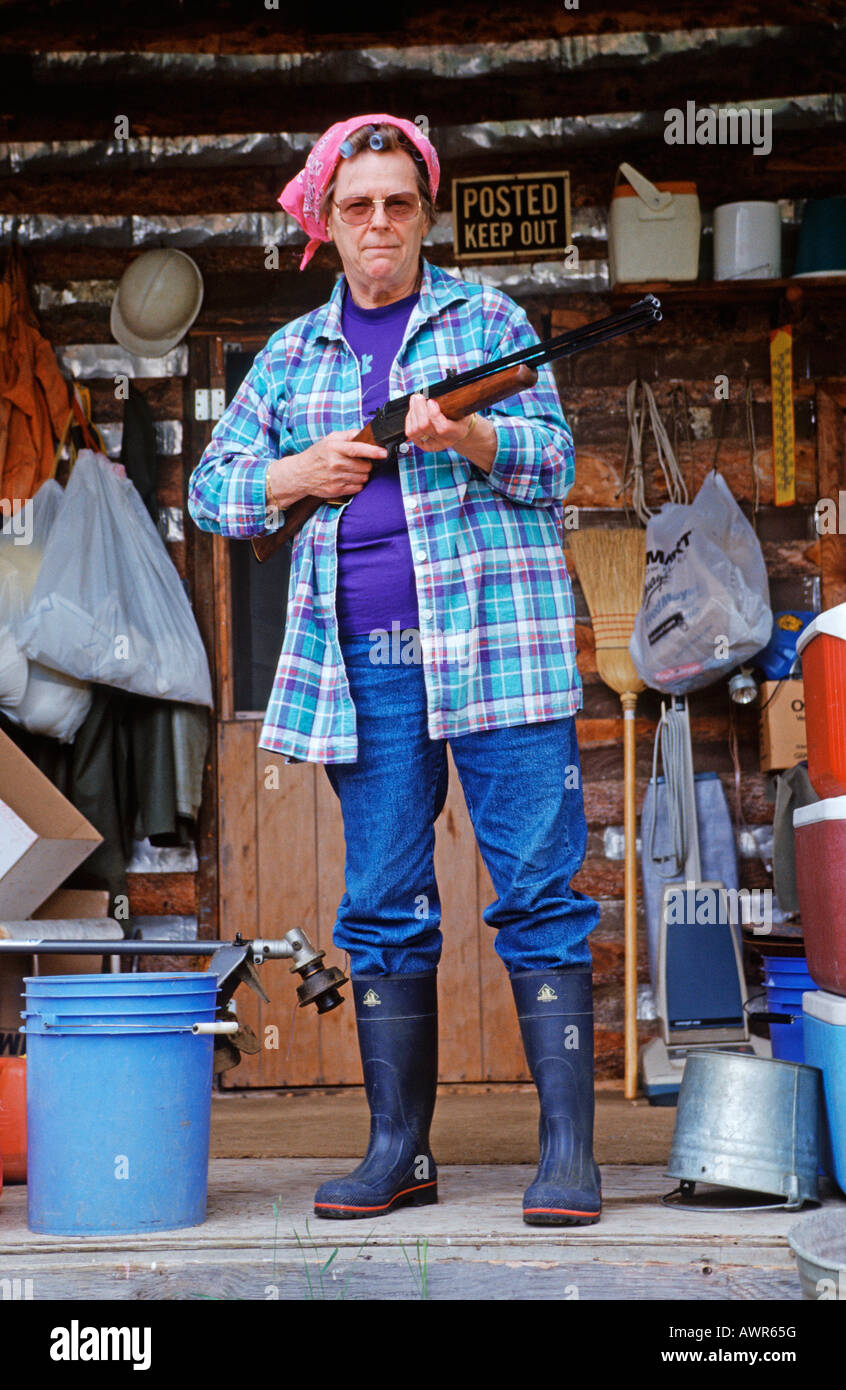 Armed woman standing in front of her log home, Brooks Range, Alaska ...