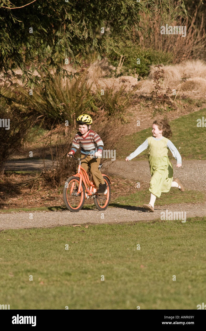 boy on bike girl running beside him Stock Photo - Alamy
