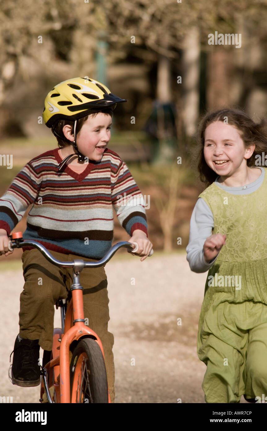 boy on bike girl running beside him Stock Photo - Alamy