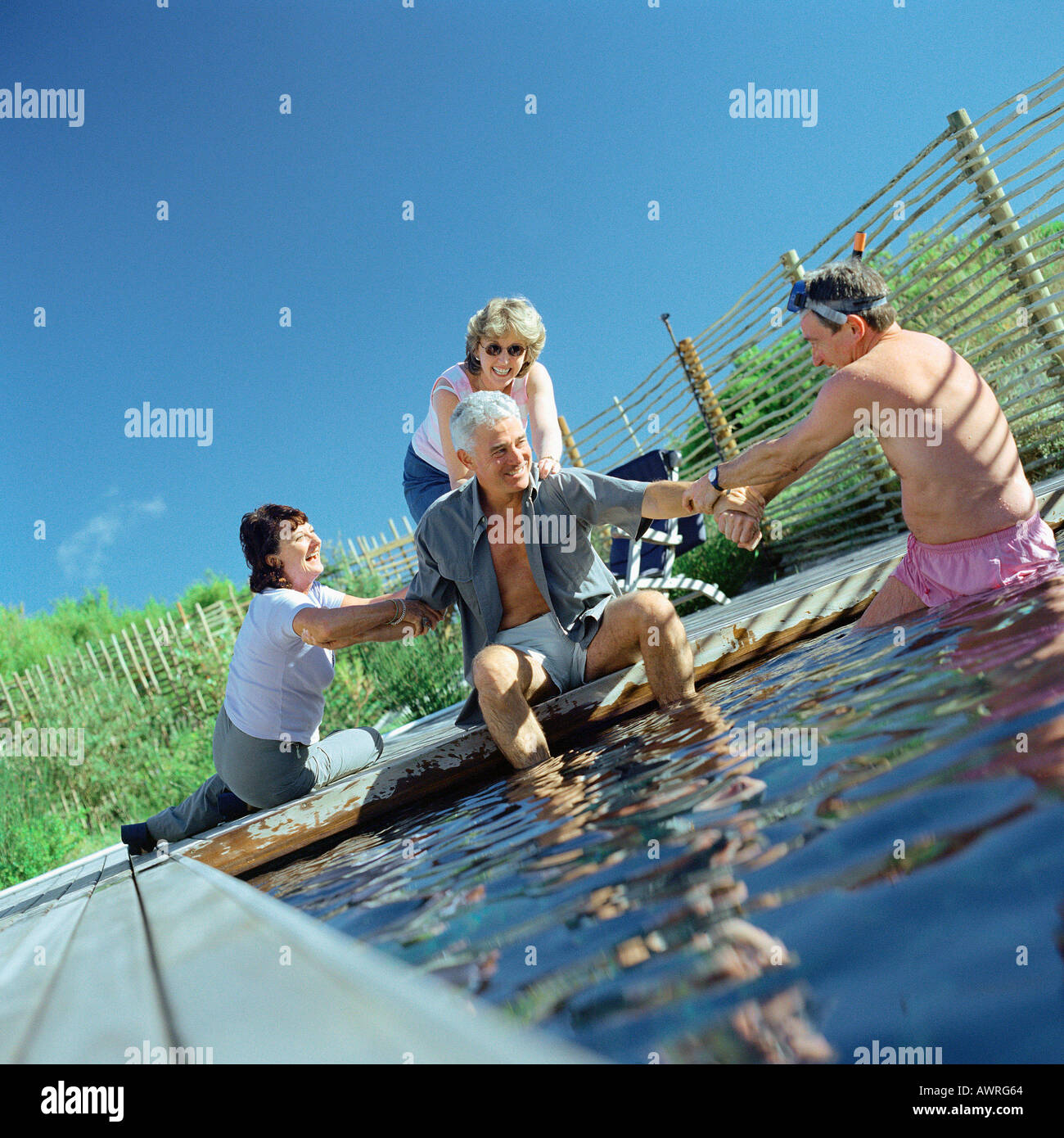 Three people trying to push a man into water Stock Photo - Alamy