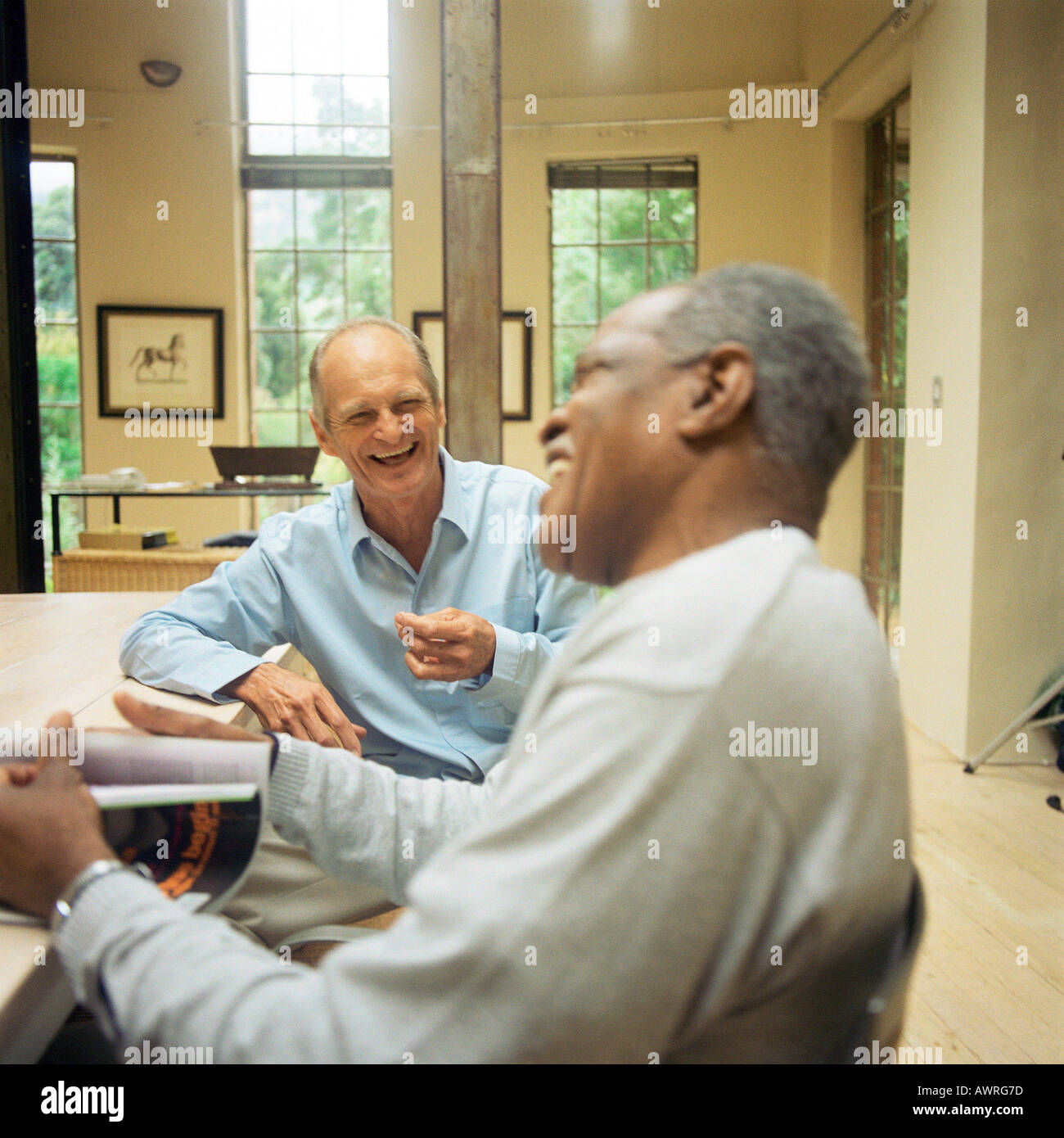 Two mature men sitting at table, laughing Stock Photo - Alamy