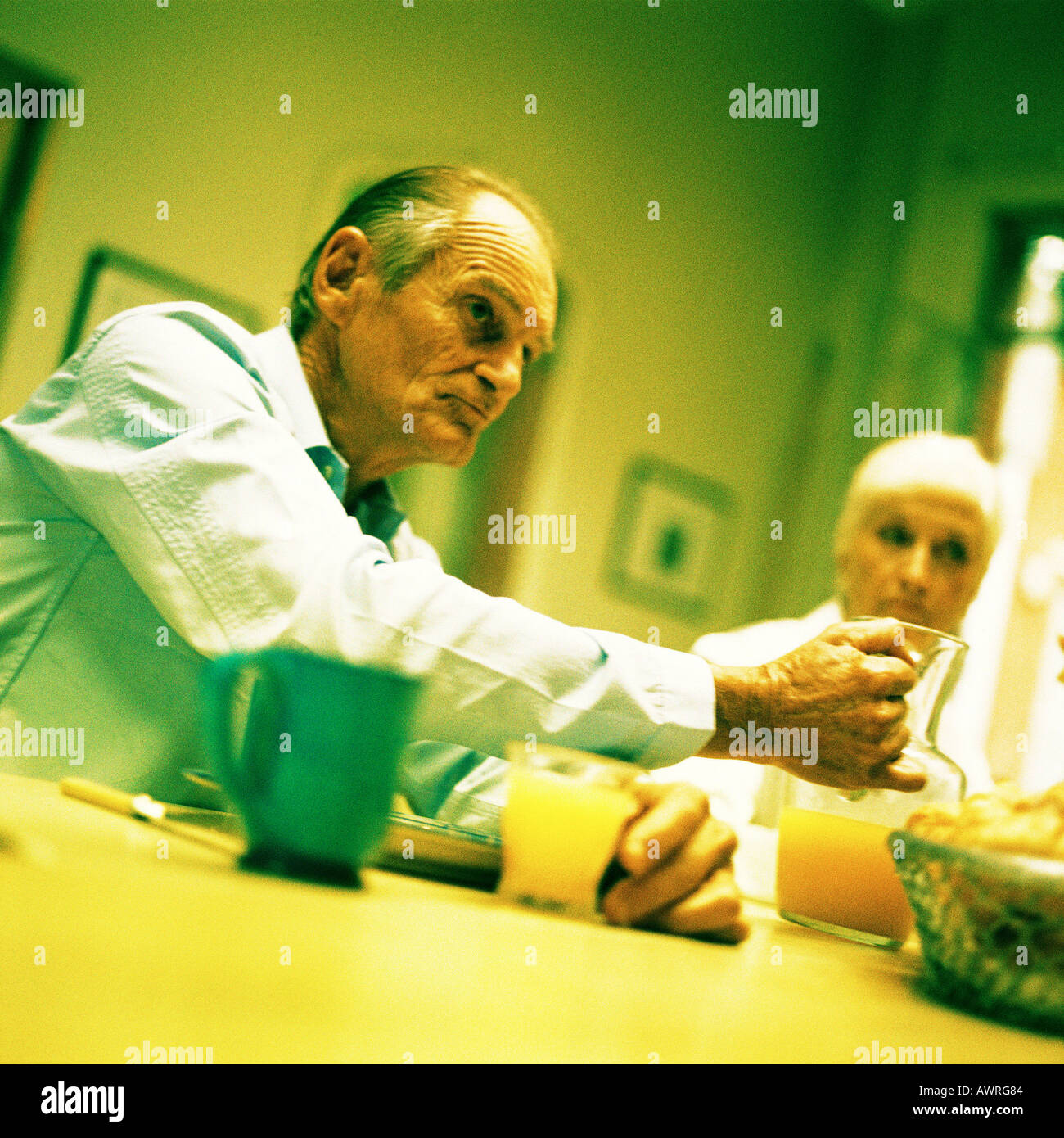 Mature couple sitting at table, man holding pitcher Stock Photo - Alamy
