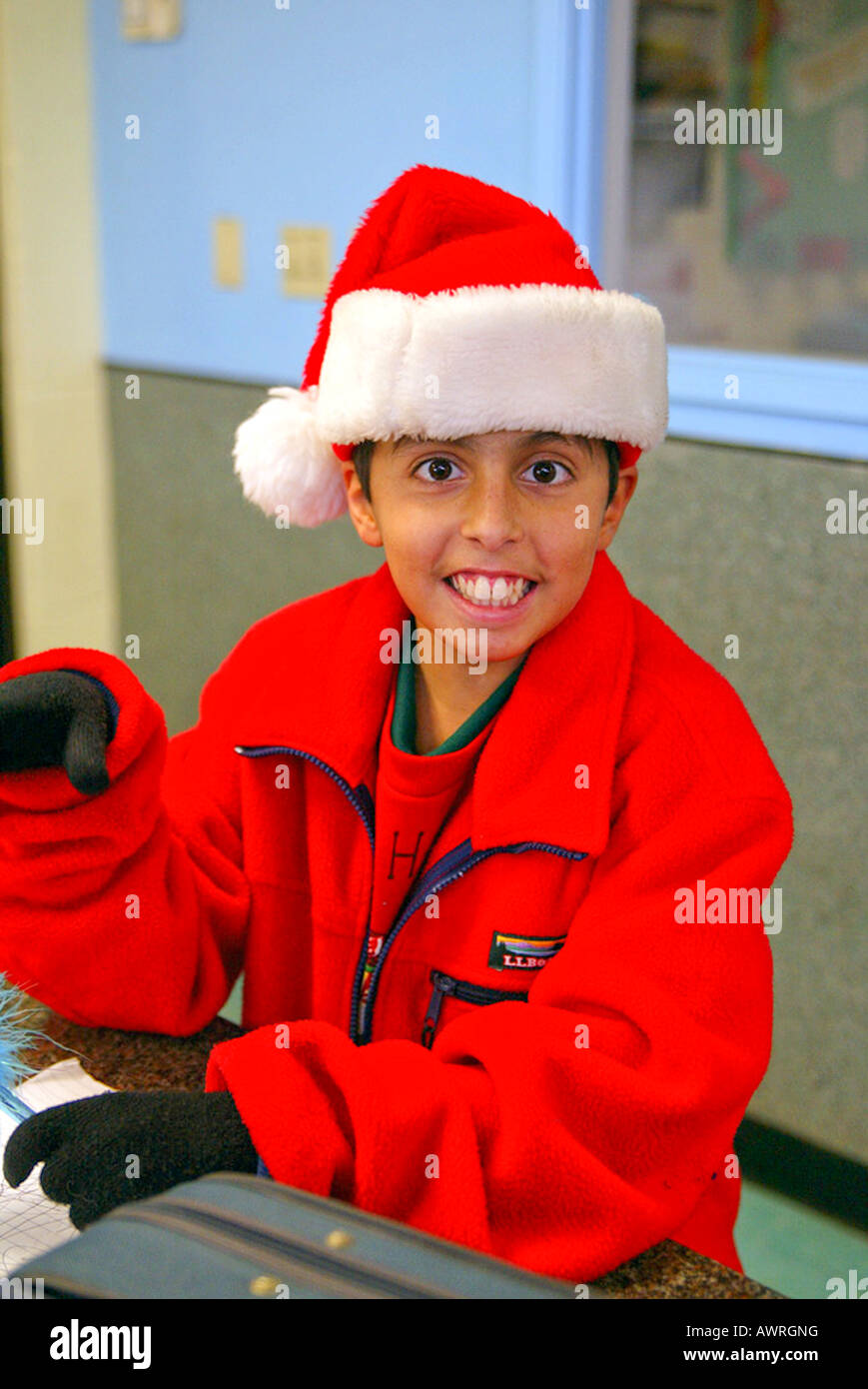 Hispanic boy wearing santa cap smiles for camera at recreation center ...