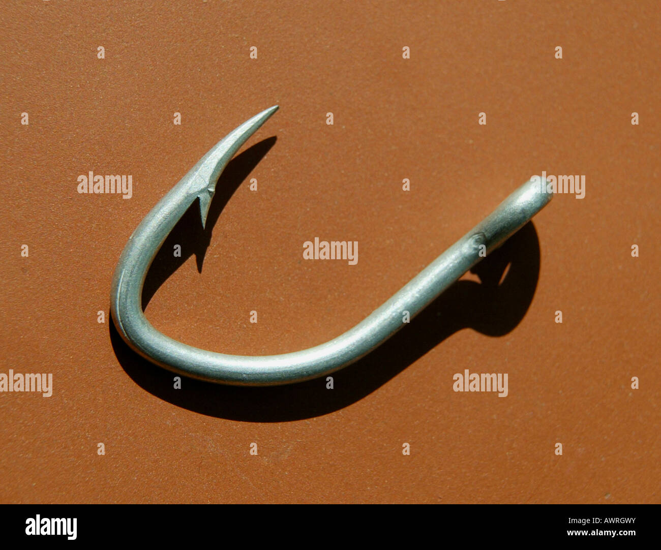 Silver fishing hook with barbed point on orange background Stock Photo ...